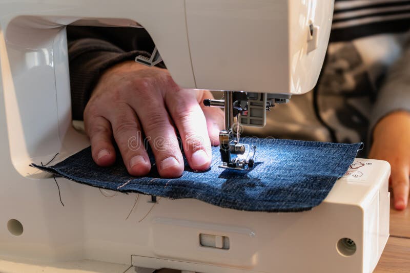 Man Using a Sewing Machine with a Blue Garment, for Repair Work ...