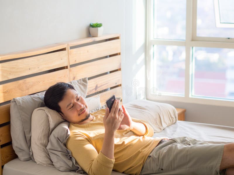 Man Using Smartphone in His Bed in the Morning. Stock Image - Image of ...