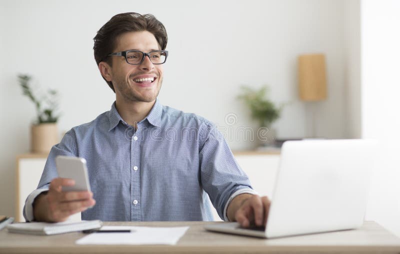 Man Using Smartphone Sitting in Front of Laptop in Office Stock Photo ...