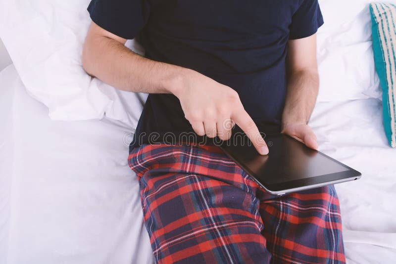 Man using tablet on bed. stock photo. Image of electronic - 96096320