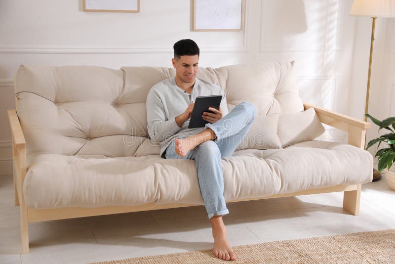 Man Using Tablet on Sofa at Home Stock Photo - Image of happy ...