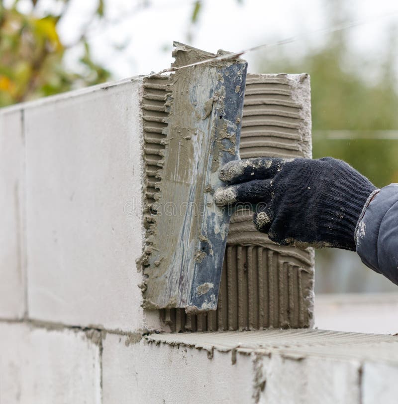 A Man is Using a Trowel To Apply Cement To a Wall Stock Image - Image ...