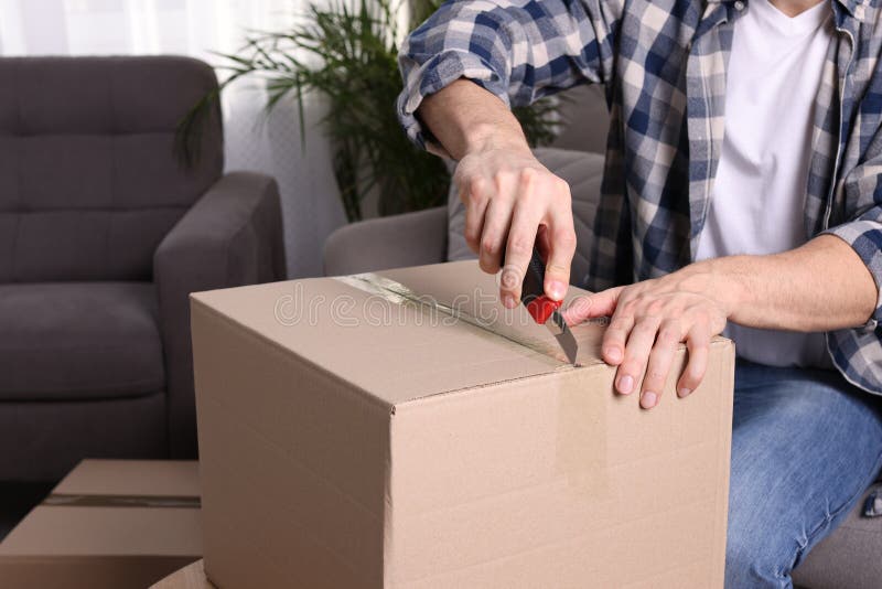 Man Using Utility Knife To Open Parcel at Home, Closeup Stock Image ...