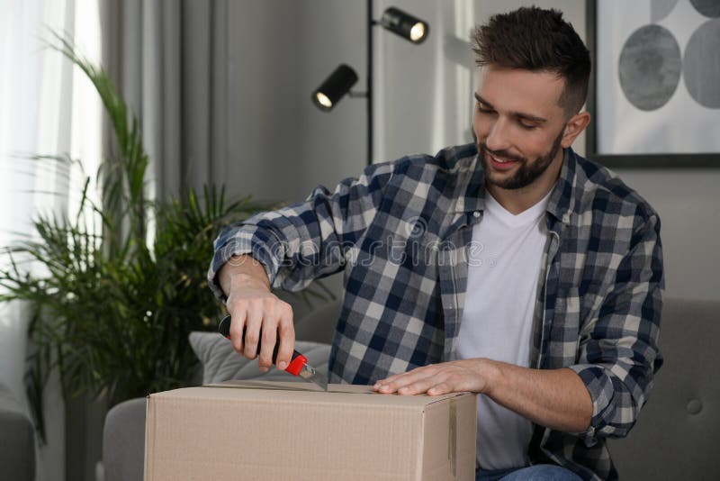 Man Using Utility Knife To Open Parcel at Home Stock Image - Image of ...