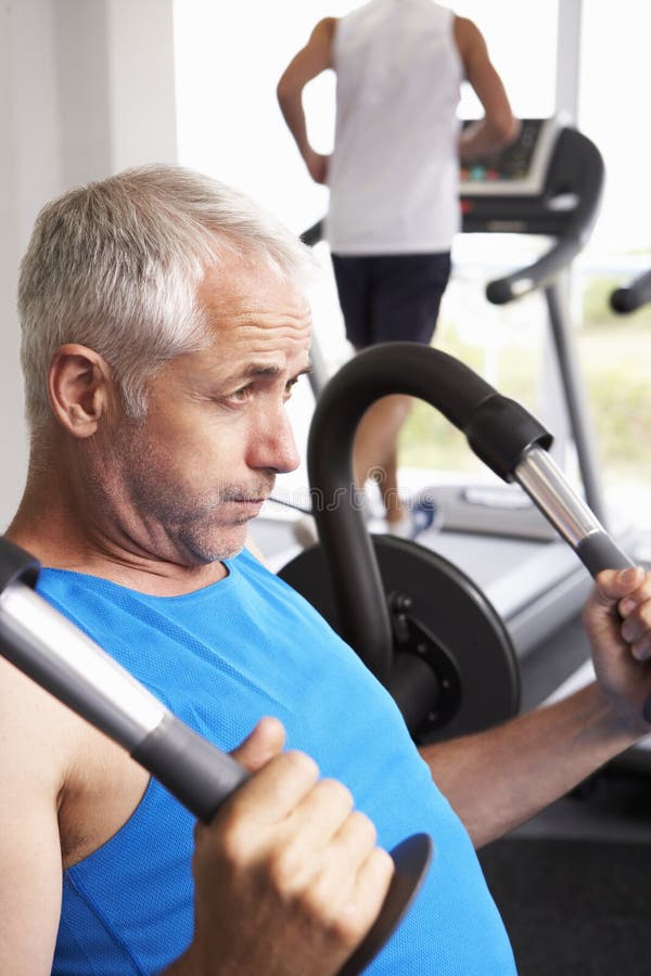 Man Using Weights Machine with Runner on Treadmill in Background Stock ...