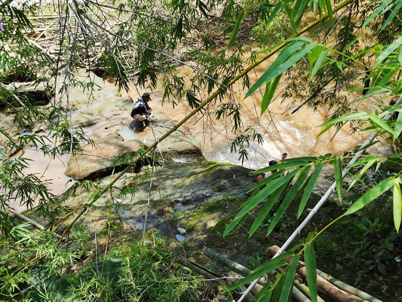 A Man Waiting for Fishing Results on a River Rock Stock Image - Image ...