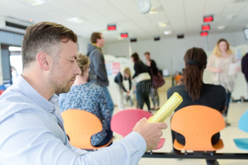 Man in Waiting Room Reading Paperwork Stock Image - Image of doctor ...