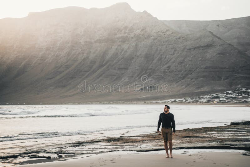Man Walking Along the Beach at Sunset Stock Image - Image of silhouette ...