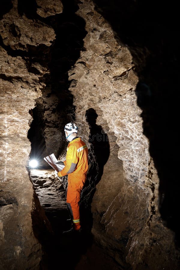 Man Walking and Exploring Dark Cave with Light Headlamp and Map in His ...