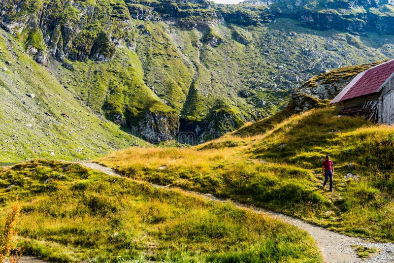 Man Walking on a Mountain Path Near Mountain Chalet with Mountain in ...