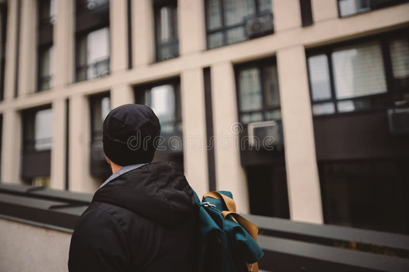 A Man Walks Against the Backdrop of Modern Urban Architecture. he is ...