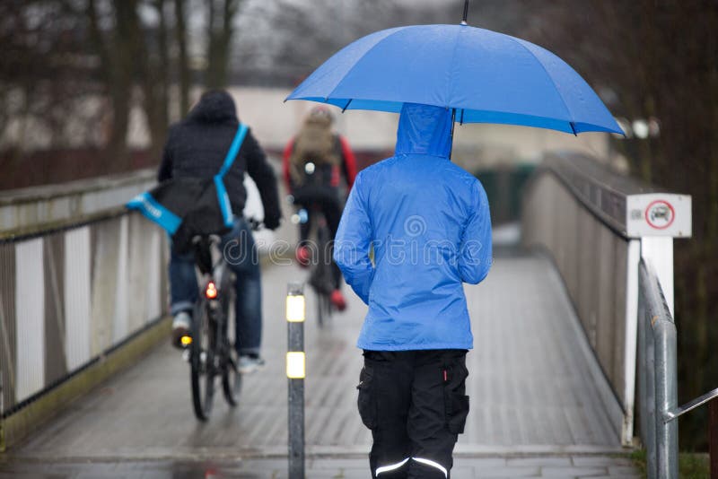 Man Walks in the Rain with His Umbrella and Raincoat Over a Bridge ...