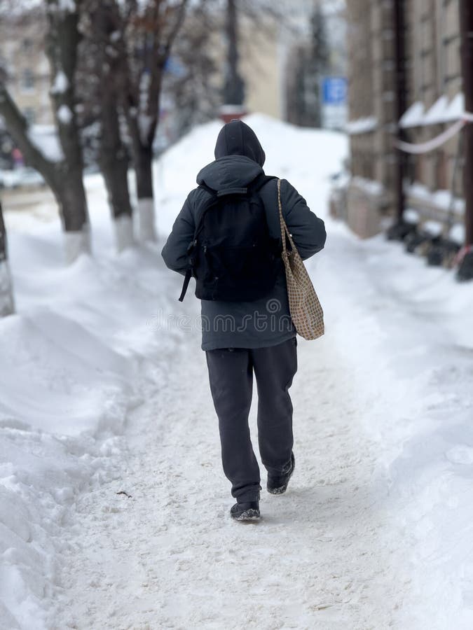 A Man Walks through the Snow in the City in Winter. Back View Stock ...