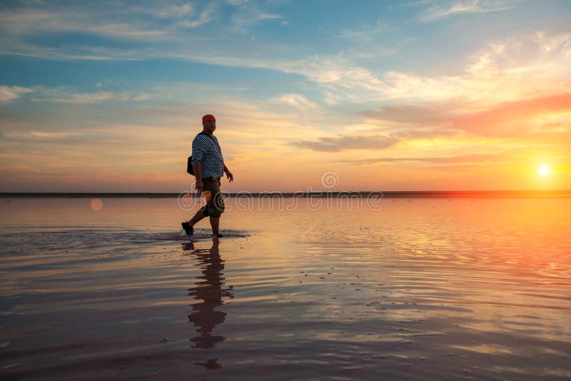 A Man Walks on the Water with the Reflection of the Sunset Sky Stock ...