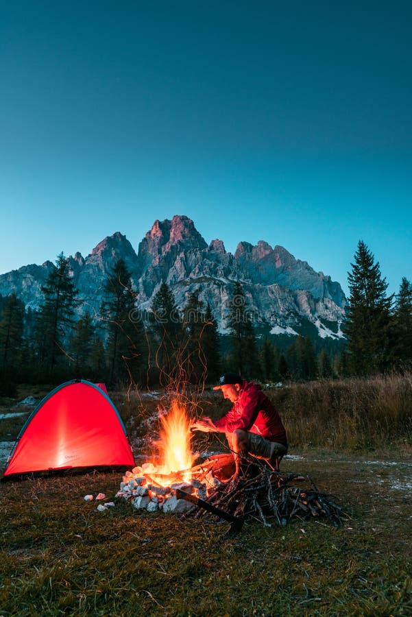 Man Warming Hands by Campfire in Mountains. Red Illuminated Tent at ...
