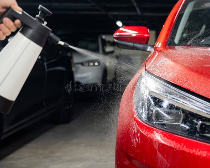 A Man Washes the Headlights of a Red Car with a Spray. Stock Photo ...