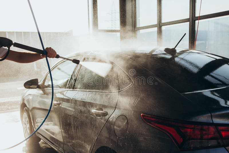 A Man Washes His Car at a Self-service Car Wash Using a Hose with ...