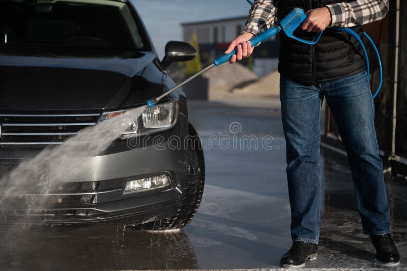 A Man Washes His Car at a Self Service Car Wash Using a Hose with ...