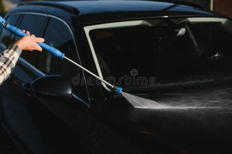 A Man Washes His Car at a Self Service Car Wash Using a Hose with ...