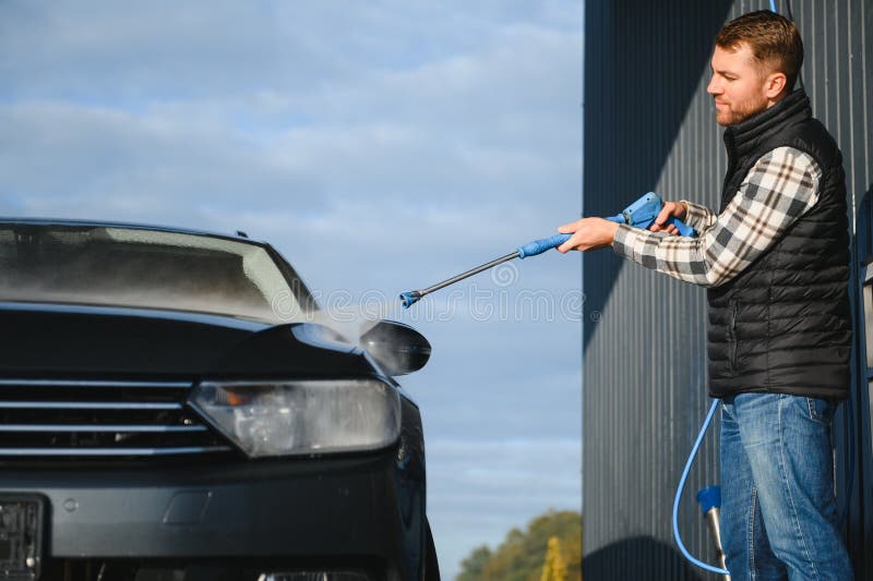 A Man Washes His Car at a Self Service Car Wash Using a Hose with ...