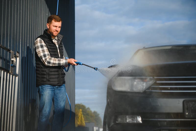 A Man Washes His Car at a Self Service Car Wash Using a Hose with ...