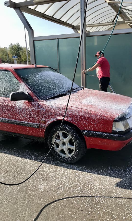 A Man Washes a Red Car at a Car Wash with Detergent. Stock Photo ...