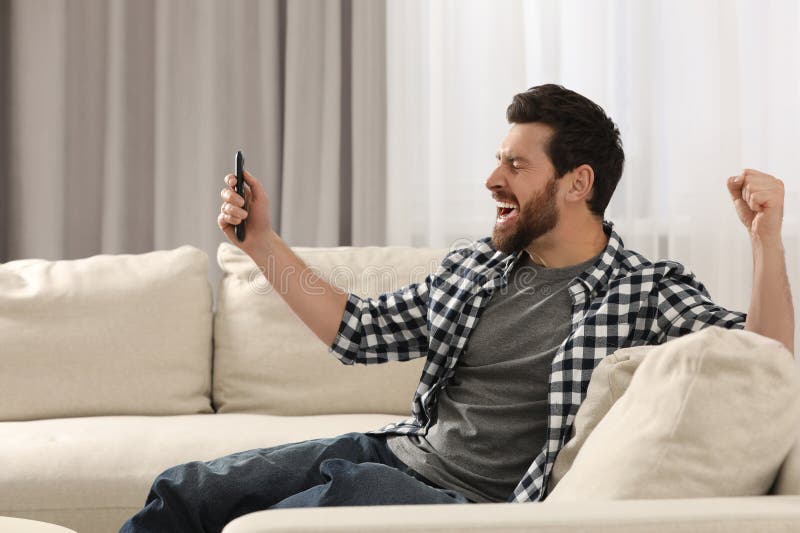 Excited Man Watching TV on Sofa at Home Stock Photo - Image of ...
