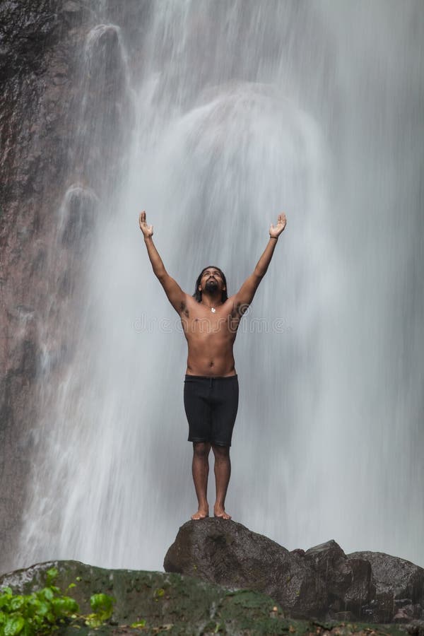 Man with Arms Outstretched Meditating Against Waterfall Stock Image ...