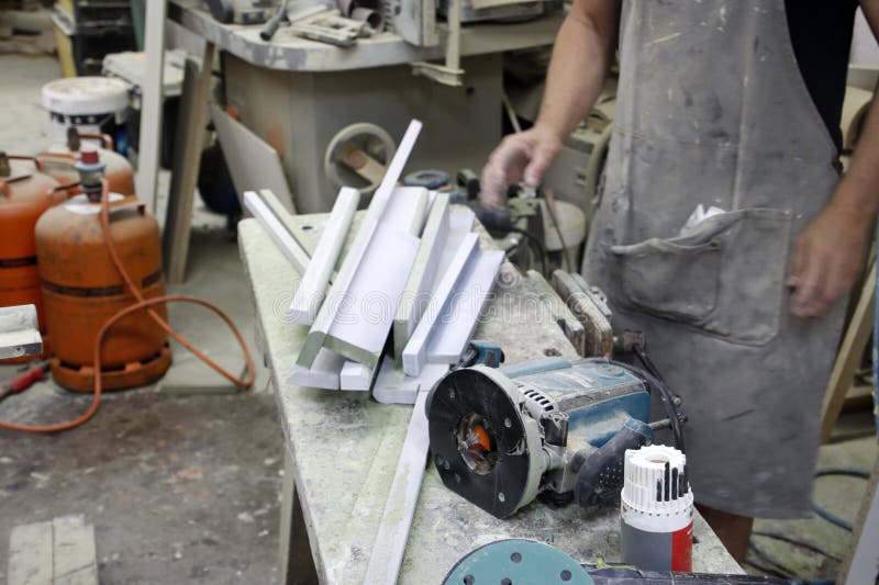 A Man Wearing an Apron Using a Power Tools Machine in a Workshop Stock ...