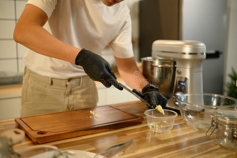 Man Wearing Black Gloves Chopping Garlic for Meal Prep in a Modern ...