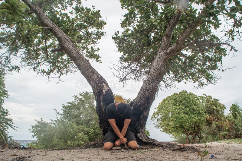 Man Wearing Black Standing on Knees and Looking Down in Front of Burned ...
