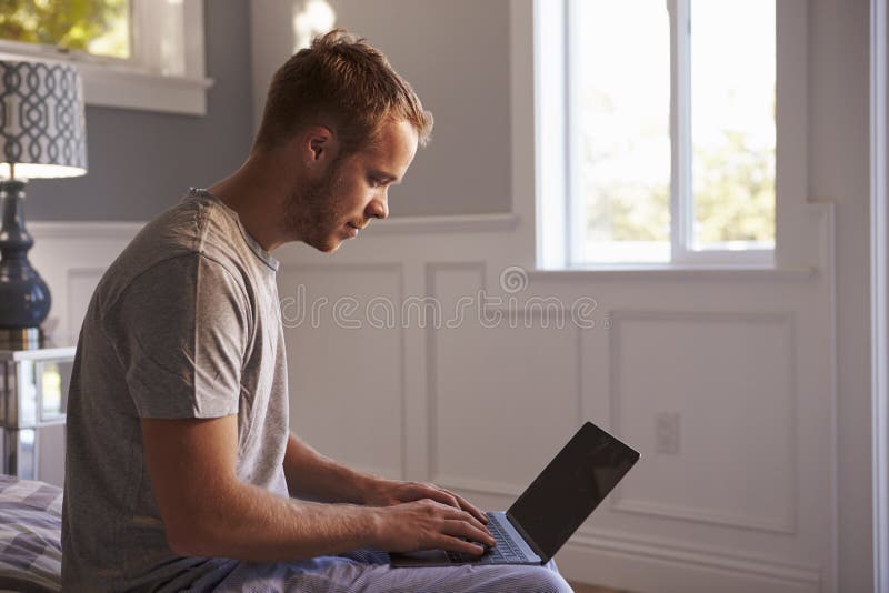 Man Wearing Pajamas Using Laptop Computer in Bedroom Stock Photo ...