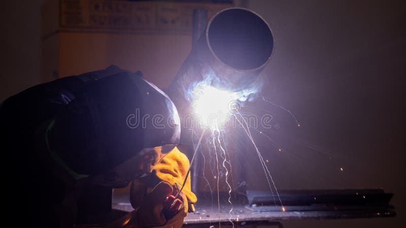 A Man Wearing a Protective Mask Welds a Metal Pipe. Stock Image - Image ...