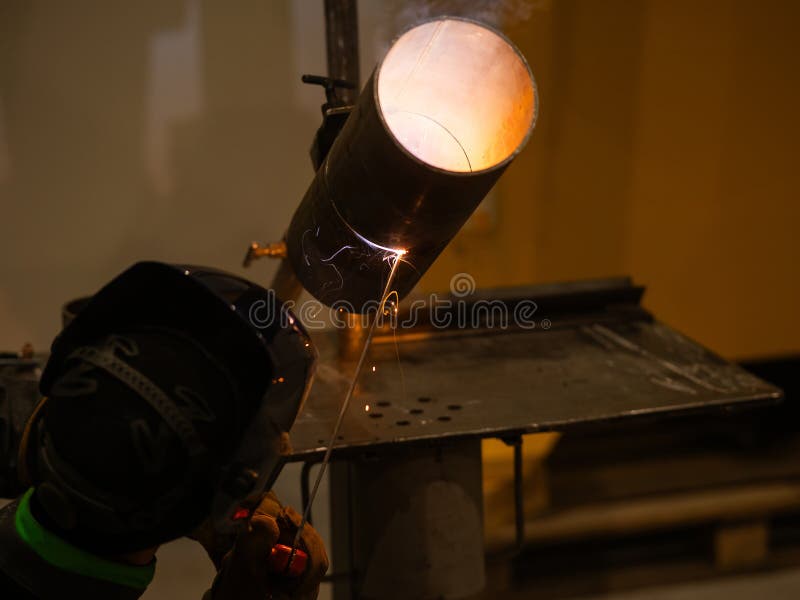 A Man Wearing a Protective Mask Welds a Metal Pipe. Stock Image - Image ...