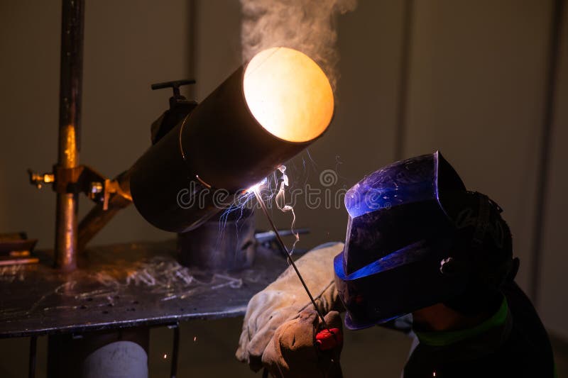 A Man Wearing a Protective Mask Welds a Metal Pipe. Stock Photo - Image ...