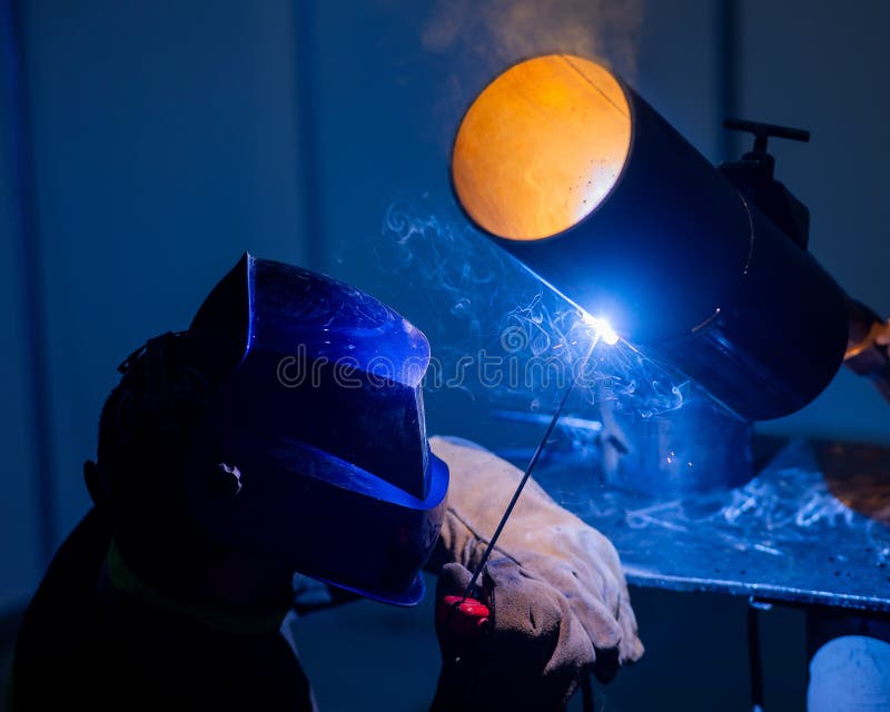 A Man Wearing a Protective Mask Welds a Metal Pipe. Stock Photo - Image ...