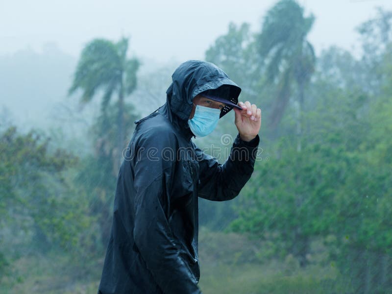 Man Wears Face Mask and Raincoat Under Heavy Tropical Rain. Stock Image ...