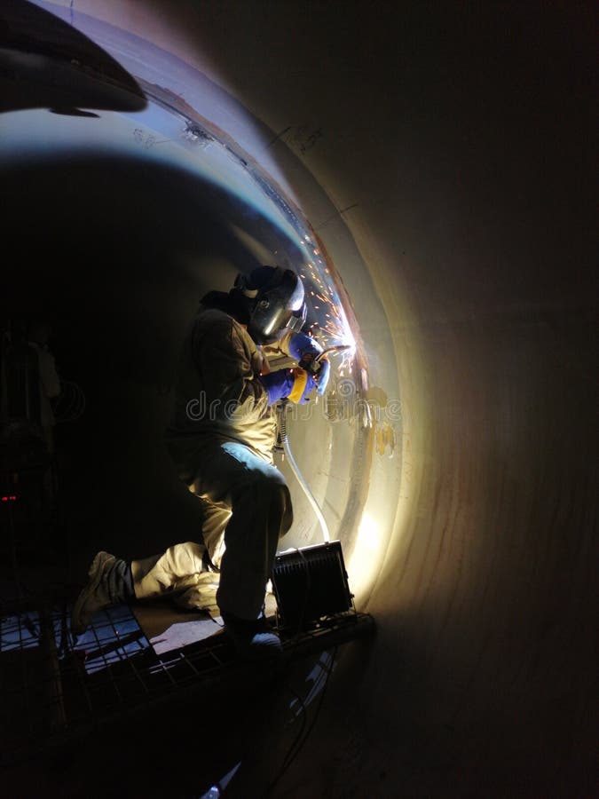 Man Welding inside a pipe stock photo. Image of stage - 219907968