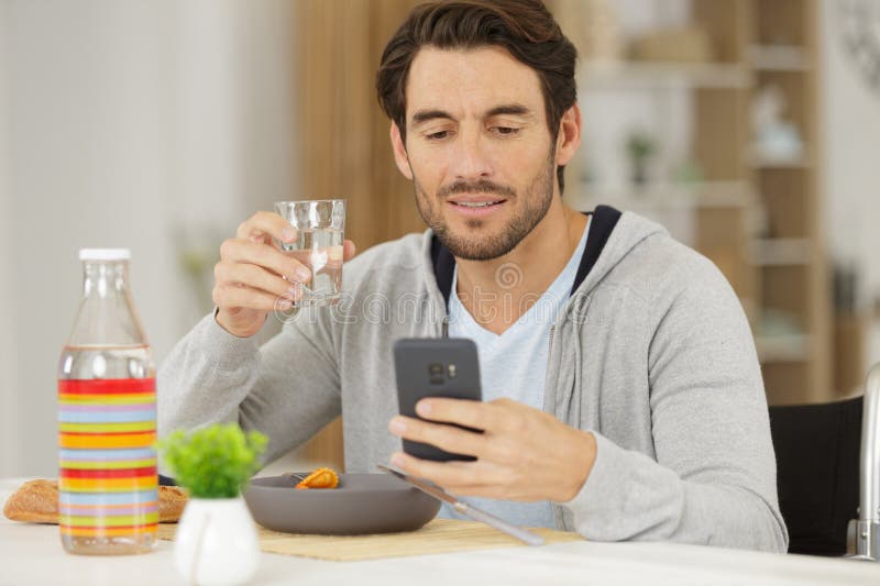 Man in Wheelchair Using Smartphone while Eating Meal Stock Photo ...