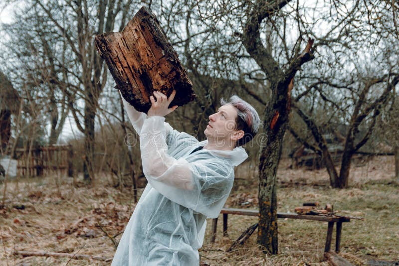 A Man in a White Protective Suit, Overalls and an Old Tree, a Stump ...