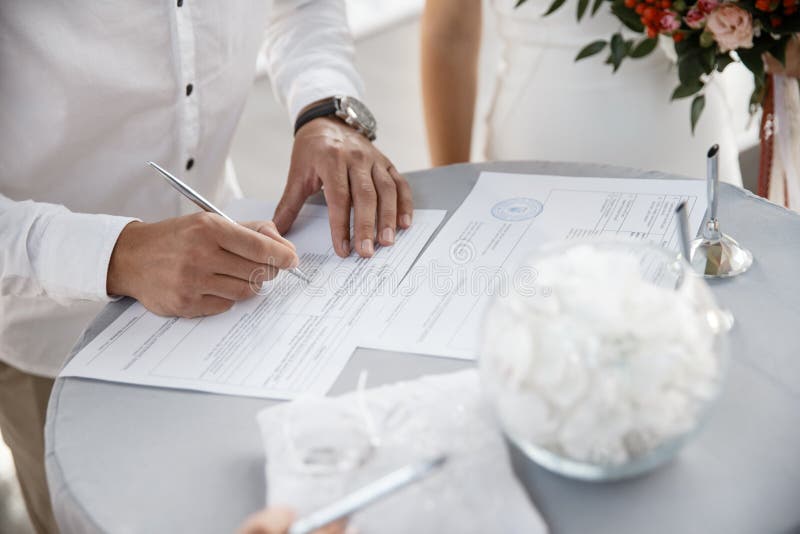 A Man in a White Shirt is Signing Up a Document in a Registry Office ...