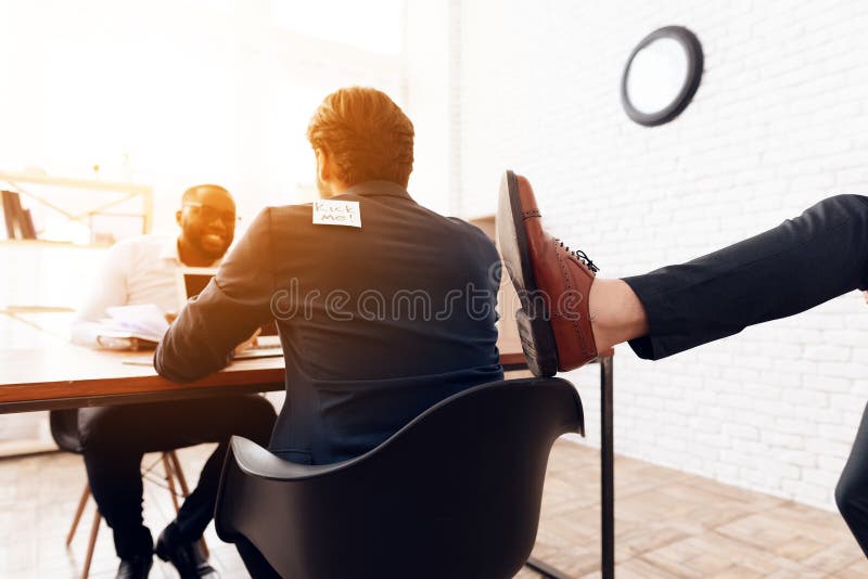 A Man Whose Back is Written Kick Me, Someone is Kicking. Stock Image ...