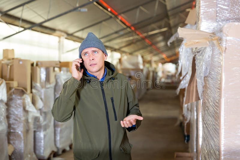 Man in Winter Clothes Talking on Mobile Phone in Warehouse Stock Photo ...