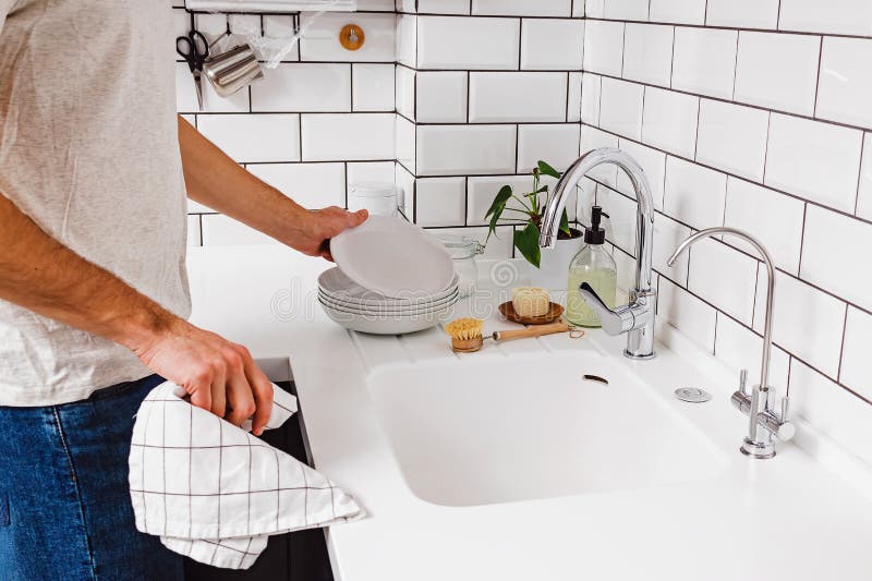 A Man Wipe Off with a Towel Dishes in the Kitchen with White Tiles ...