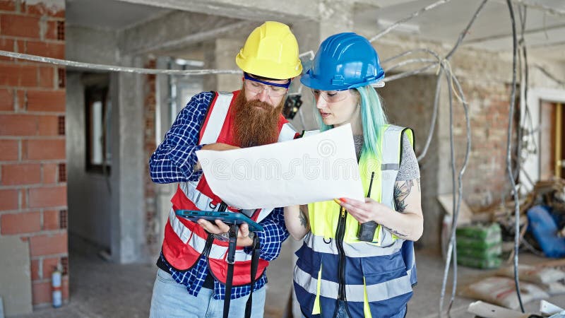 Man and Woman Builders Using Touchpad Reading House Project at ...