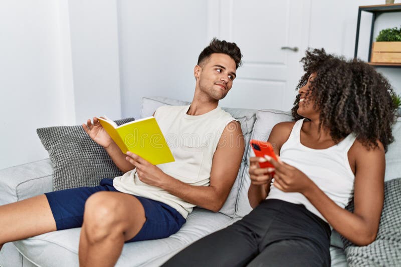 Man and Woman Couple Using Smartphone Reading Book at Home Stock Image ...