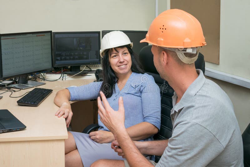 A Man and a Woman in Engineering Helmets are Talking in Front of the ...