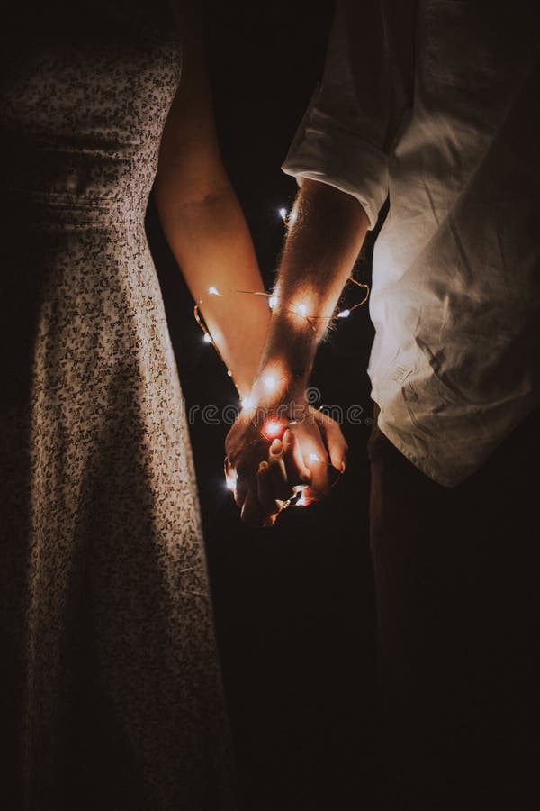 Man And Woman Holding Each Others Hand Wrapped With String Lights ...
