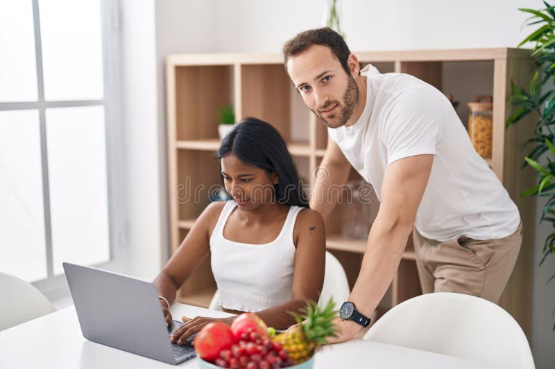 Man and Woman Interracial Couple Using Laptop Sitting on Table at Home ...