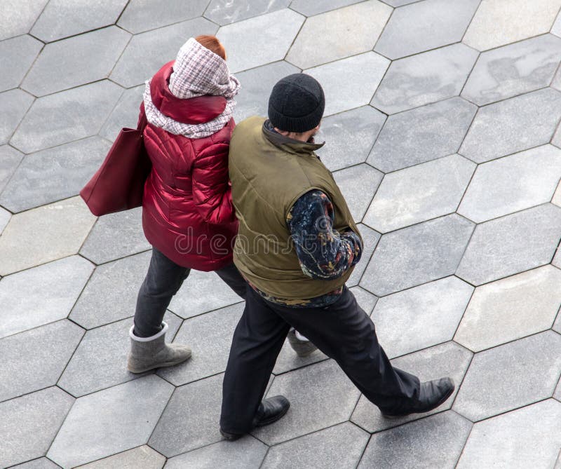 A Man with a Woman in Jackets are Walking Along the Pavement Stock ...